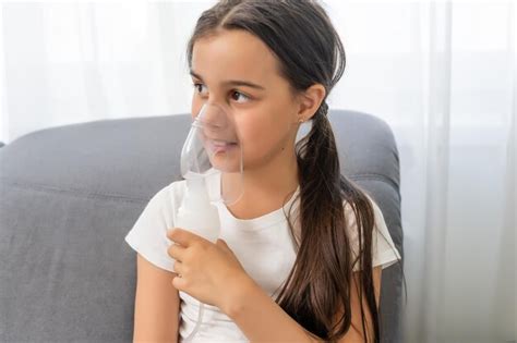 집에서 분무기로 흡입하는 어린 소녀 어린이 천식 흡입기 흡입 분무기 증기 아픈 기침 개념 프리미엄 사진