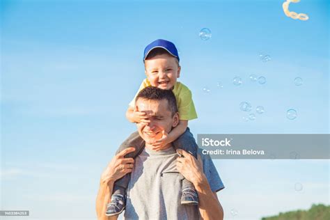 아버지의 어깨에 어린 소년 해질녘에 야외에서 산책하고 재미있게 놀고 비누 거품을 잡는 작은 두 살짜리 아이 아들과 함께 행복한 남자 2 3 살에 대한 스톡 사진 및 기타