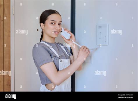 Teenage Girl Holding Intercom Handset While Talking To Guest Stock
