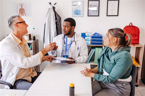 진료실에서 여성 환자를 진찰하는 의사가 의료 보조원과 함께 건강 상태를 확인하고 있습니다 20 24세에 대한 스톡 사진 및 기타 이미지 20 24세 25 29세 50