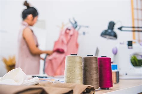 워크샵 스튜디오에서 패션 디자이너 배경과 다채로운 스레드의 클로즈업 새로운 천 디자인 컬렉션을 만드는 세련된 패셔니 스타 여성 사람들의 생활 방식과 직업을 재봉하고 바느질