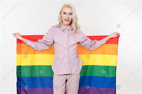 Young Blond Haired Person In Pastel Pjs And A Rainbow Flag In Their Hands Standing Against The