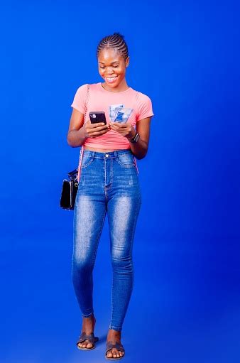 자신감 넘치고 행복한 흑인 여성이 생생한 파란색 배경에 현금과 전화기를 들고 있다 결심에 대한 스톡 사진 및 기타 이미지 결심 긍정적인 감정 표현 명랑한 Istock