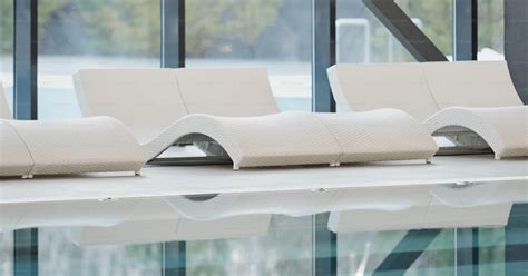 현대적인 호텔 스파 또는 레저 센터 내부에 투명한 물이 있는 큰 창문과 수영장을 따라 서 있는 흰색 데크 의자 사진 Unsplash의 테이블 이미지