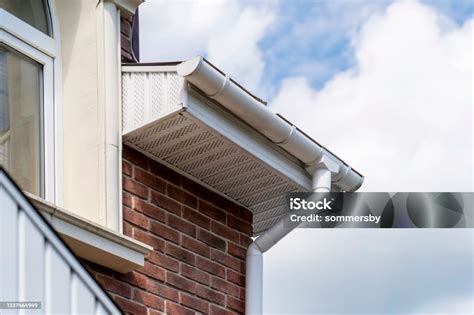 벽돌 고급 주택의 모퉁이에 Soffit 통풍구 배수구 가드 다운 스푸트 장식 트림 성형 오래된 흰색 거터 시스템의 클로즈업 보기 지붕용 홈통에 대한 스톡 사진 및 기타