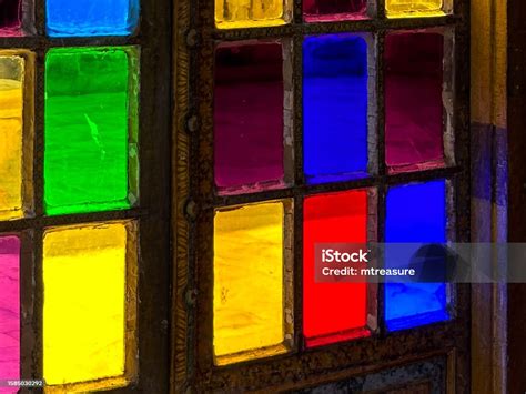 무거운 나무 문에 있는 스테인드 글라스의 여러 가지 빛깔의 창 창문을 통해 흐르는 빛 분홍색 청록색 빨간색 파란색 노란색 및 녹색 사각형 유리의 전체 프레임 이미지 0명에