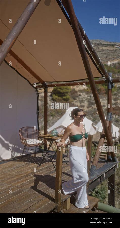 Hispanic Young Woman In A Green Bikini And White Pants Enjoys Camping