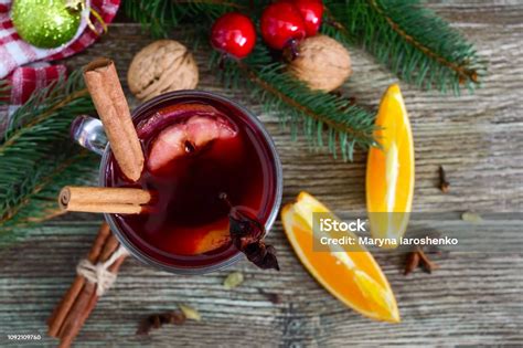 나무 테이블에 유리 머그잔에 뜨거운 Mulled 와인 향기로운 전통적인 겨울 음료 와인 주스 향신료 조미료 과일에 따라 닫습니다