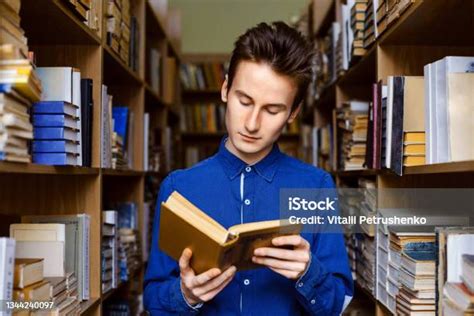 도서관에서 책을 읽고 다른 오래된 책의 선반의 통로 사이에 서 있는 남성 학생 20 24세에 대한 스톡 사진 및 기타 이미지
