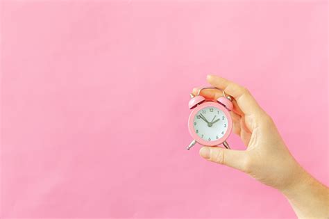 분홍색 파스텔 컬러풀한 트렌디한 배경에 분리된 트윈 벨 알람 시계를 들고 있는 여성 핸드를 디자인하는 심플한 디자인 개념에 대한 스톡 사진 및 기타 이미지 Istock