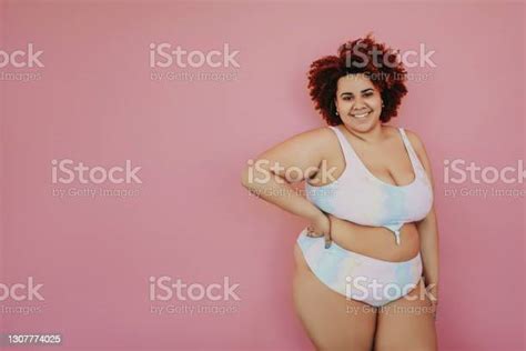 행복한 미소 감정적 인 매력적인 오버사이즈 아프리카 흑인 여성 아프로 헤어 포즈 수영복 핑크 배경 고립 신체 불완전 신체 수용