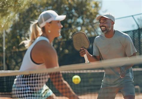 A Man And Woman Playing Tennis With A Woman Wearing A Hat Premium Ai