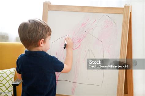 아이가 집에서 아이와 아이 들을 위한 나무 드로잉 보드 아티스트이 젤의 종이에 펠트 펜으로 그림을 그리는 것입니다 어린 시절
