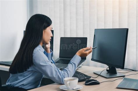 Concentrated Asian Woman Brainstorming While Coding Data On Desktop Pc While Working On Computer