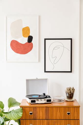 디자인 Commode와 거실의 빈티지 복고 인테리어 비닐 레코더 선인장과 흰색 벽에 포스터를 모의 갈색 나무 마루와 식물이 있는 아늑한 객실입니다 0명에 대한 스톡 사진 및