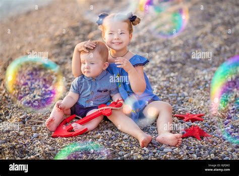 Brother And Sister Playing In The Shore Break On The Beach During The