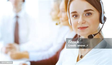 햇볕이 잘 드는 사무실에서 직장에서 다양한 전화 사업자의 그룹 헤드폰 컨설팅 클라이언트와 잘 생긴 비즈니스 여성 콜 센터 및