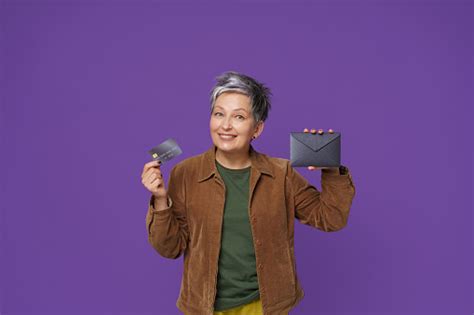 화려한 어두운 봉투와 성숙한 여성 손에 선물 카드 행복한 성숙한 여성은 보라색 배경에 고립 된 캐주얼을 입은 새로운 은행 직불 신용 카드를 받았습니다 은행 금융 개념 여자에