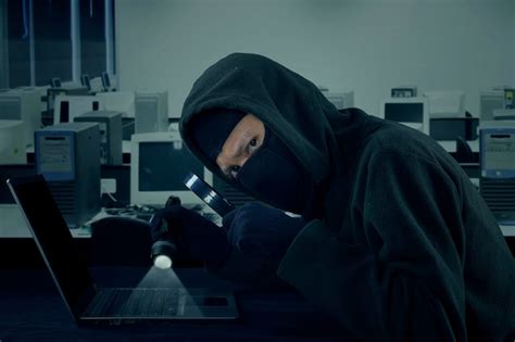 Premium Photo Computer Hacker Holding Illuminated Flash Light And Magnifying Glass Over Laptop