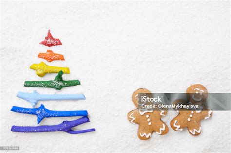 눈 배경에 무지개 색상과 진저 브레드 쿠키로 그린 작은 나뭇 가지로 만든 플랫 누워 양식에 일치시키는 크리스마스 트리 텍스트를