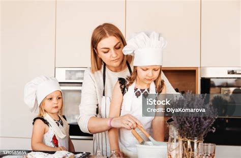 행복한 엄마와 부엌에 함께 서있는 두 딸은 빵집을 만드는 방법을 배울 준비가되어 있습니다 가족 관계에 대한 아이디어 3 명에
