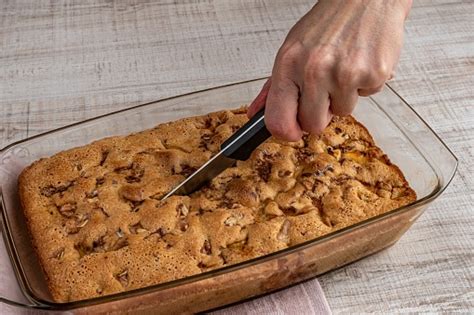 테이블에 있는 유리 그릇에 담긴 과일과 베리 파이는 칼로 같은 부분으로 자른다 칼로 수제 파이를 자르는 여성의 손 클로즈업 딸기와 과일로 맛있고 달콤한 파이를 요리하는 개념