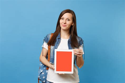 영 빈 블랙 빈 화면 파란색 배경에 고립 된 태블릿 Pc 컴퓨터를 들고 배낭 데님 옷에서 여자 학생을 꽤 고등학교에서 교육입니다 광고에 대 한 공간을 복사 합니다 20 29