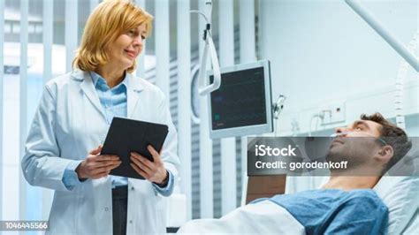 친절 한 여성 의사 방문 웃 고 복구 사람 그녀가 그에 게 질문 및 의료 차트를 채웁니다 침대에 누워 침실용 탁자에 대한 스톡 사진 및 기타 이미지 Istock