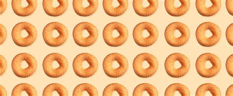 창조적 인 음식 베이킹 패턴 베이지 색 배경에 참깨가있는 신선한 둥근 밀 베이글 바삭바삭한 빵 건강한 유기농 식품 전통 페이스트리 베이커리 제품 아침 베이글 긴 배너 0명에