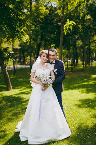 아름 다운 결혼식 Photosession입니다 블루 정장 양복과 그의 우아한 신부 드레스와 베일 화창한 날에 큰 녹색 공원에서 산책에 아름 다운 Hairdress 포옹과