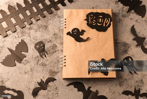 콘크리트 표면에 검은 종이로 조각 된 검은 박쥐와 유령의 그림 공예 시트와 복사 공간이있는 메모장 할로윈 축하 개념에 대한 공예품입니다 Handwork 플랫 레이 10월에