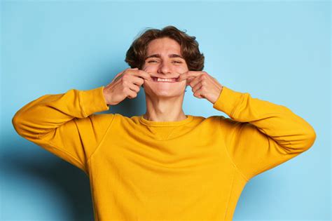 곱슬머리를 한 젊은 남자의 초상화 찡그린 얼굴 파란색 배경 위에 고립된 미소 좋은 기분 백인종에 대한 스톡 사진 및 기타 이미지 Istock