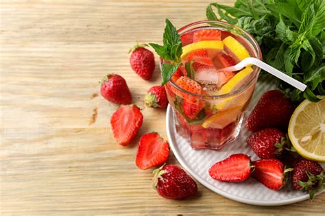 딸기 모히토 딸기 민트 레몬 얼음을 곁들인 추운 여름 모히토 칵테일은 천연 나무 테이블에 유리잔에 담겨 있습니다 여름 상쾌한 음료 감귤류 과일에 대한 스톡 사진 및 기타