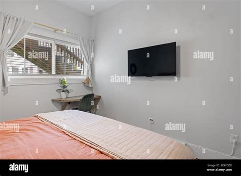 A Bedroom Featuring A Wall Mounted Flat Screen Tv Above A Cozy Bed