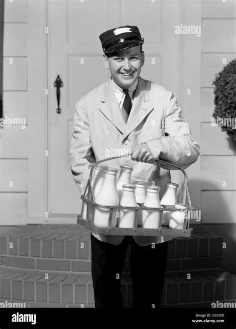 1930s Smiling Milkman Looking At Camera Delivering Milk In Glass Stock
