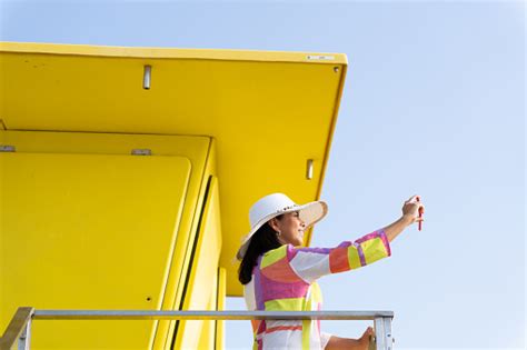 아름다운 라틴계 여성이 모자가 달린 화려한 드레스를 입고 화려한 여름날 해변 인명 구조원 기지 꼭대기에서 사진을 찍고 있다 40 49세에 대한 스톡 사진 및 기타 이미지