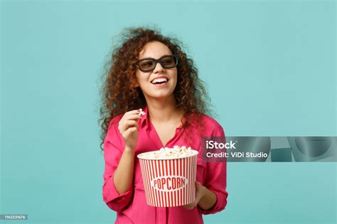 스튜디오에서 파란색 청록색 벽 배경에 고립 된 영화 필름을 보고 팝콘을 들고 3d 안경에 웃는 아프리카 소녀 영화 라이프 스타일 개념에서 사람들의 감정 복사 공간을 모의