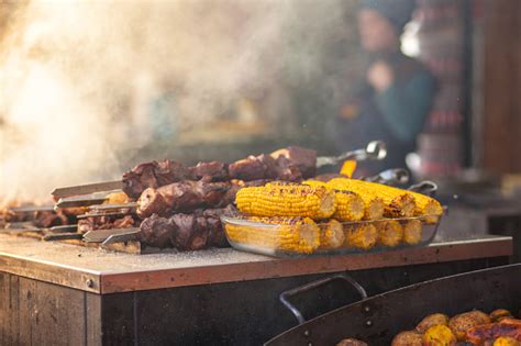 그릴에 길거리 음식 꼬치 고기와 옥수수 바베큐 배경에는 케밥을 요리하는 칼을 가진 남자의 손이 있습니다 외부 수평 사진 길거리 음식에 대한 스톡 사진 및 기타 이미지