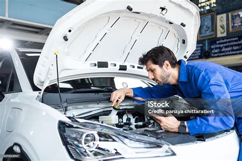 제복을 입은 정비사 남자가 고장난 전기 자동차로 작업합니다 작업장에서 일하는 동안 전기 자동차의 후드 자동차 서비스의 개념 전기 자동차 고정 에브 정비사가 수리 서비스에서