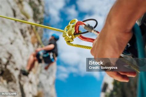절벽 등반 벽에있는 소년과 함께 Belay 장치 클로즈업 샷 그는 등반 하네스에서 밧줄에 매달려 있고 그의 파트너는 그를 땅에 눕히고 있습니다 활동적인 사람들과 스포츠 컨셉