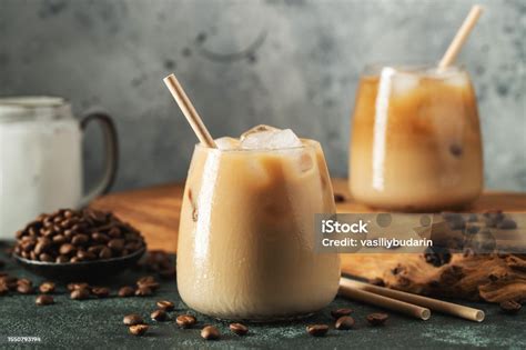 크림이 쏟아진 키가 큰 유리잔에 담긴 아이스 커피 어두운 콘크리트 테이블 위에 얼음 조각과 콩 0명에 대한 스톡 사진 및 기타