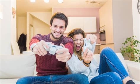 Premium Photo Portrait Of Happy Young Couple Playing Video Game While Sitting On Sofa At Home Premium Photo Portrait Of Happy Young Couple Playing Video Game While Sitting On Sofa At Home