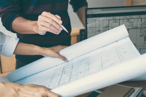 Premium Photo Midsection Of Architects Analyzing Blueprints In Office