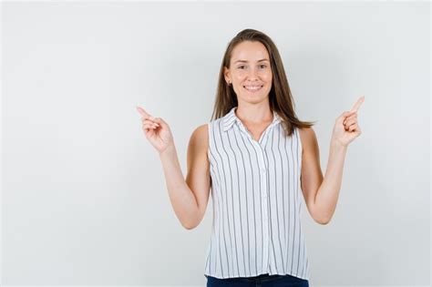 Ragazza Che Punta Le Dita In Su In T Shirt Jeans E Sembra Felice Vista Frontale Foto Gratis