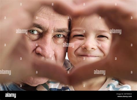 Grandfather And Grandson Making A Heart Shape Hand Gesture Together