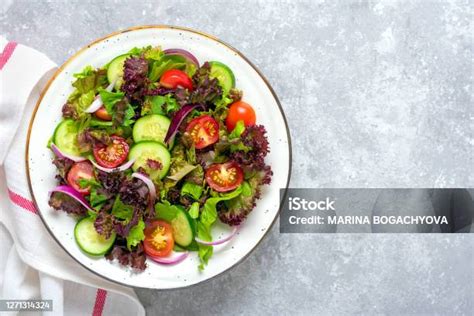 체리 토마토 오이 슬라이스 녹색과 보라색 양상추 잎 양파 올리브 오일의 건강한 야채 샐러드가 콘크리트 테이블에 접시에 담았습니다 건강한 생활방식에 대한 스톡 사진 및 기타