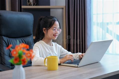Young Asian Schoolgirl Is Doing Her Class Homework Assignment At Home Using Laptop Computer For