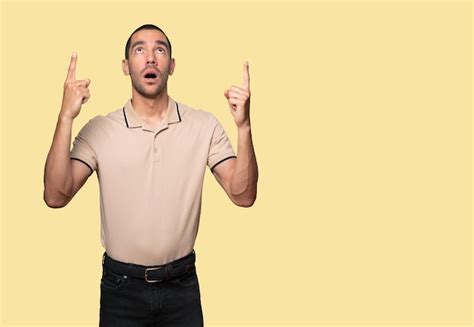 Удивленный молодой человек указывающий пальцем Премиум Фото