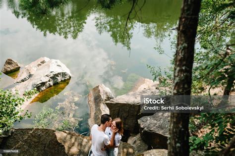 젊은 부부는 호수 근처의 돌을 껴 안고 키스를 합니다 한 남자와 여자는 바위의 배경에 서 있었다 평면도 자연 가 위쪽 절반 서로를 바라보 고 있습니다 2명에 대한 스톡 사진