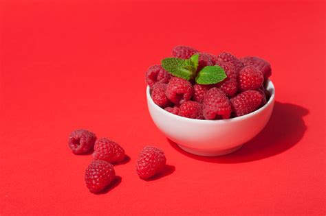 신선한 나무 딸기와 붉은 바탕에 민트 잎 그릇 공간에 복사 합니다 최소한의 개념입니다 하드 라이트 0명에 대한 스톡 사진 및